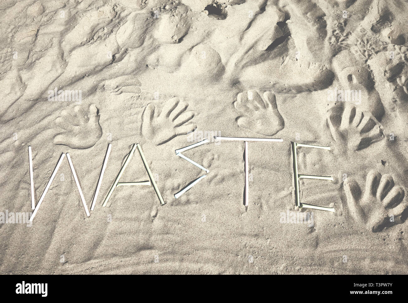 Waste word made of plastic straws on sand, retro color toned picture ...