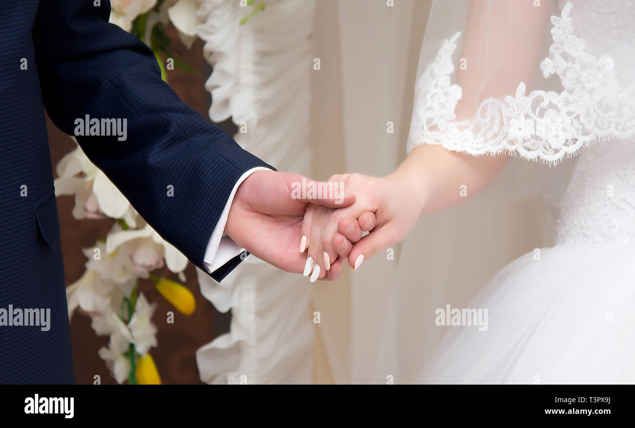 Young married couple holding hands, ceremony wedding day Stock Photo ...