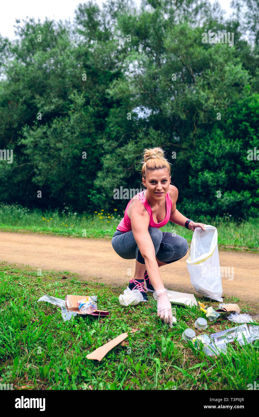 Girl picking up trash doing plogging Stock Photo - Alamy