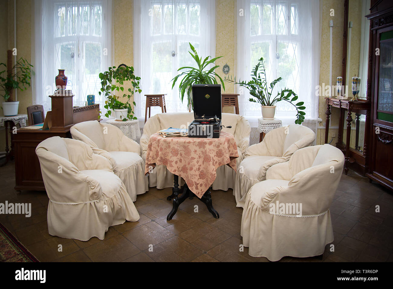 Vintage room with phonograph, chairs in white covers, sofa, round table ...