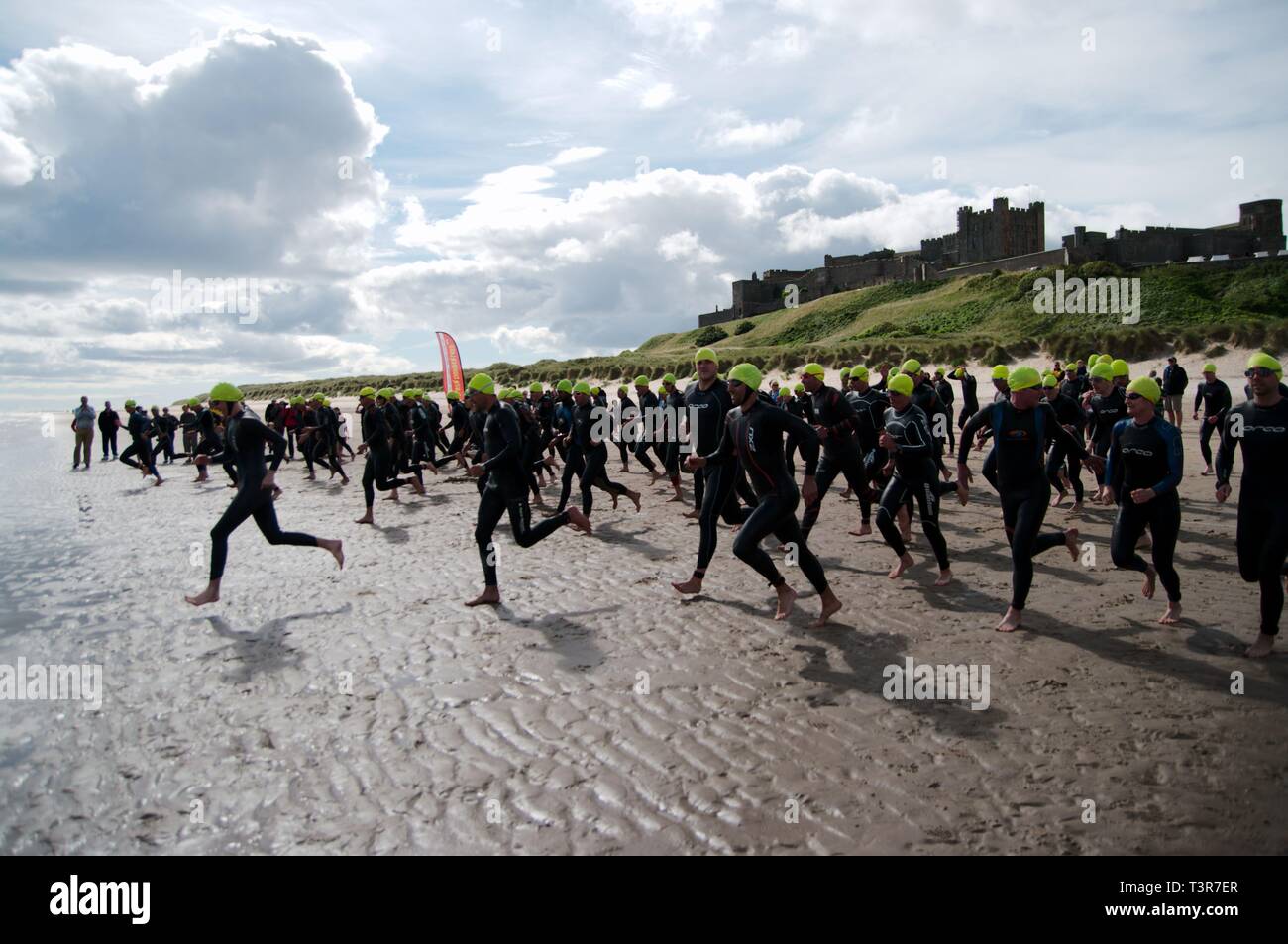 Triathletes running into the sea on the beach at Bamburgh at the start ...