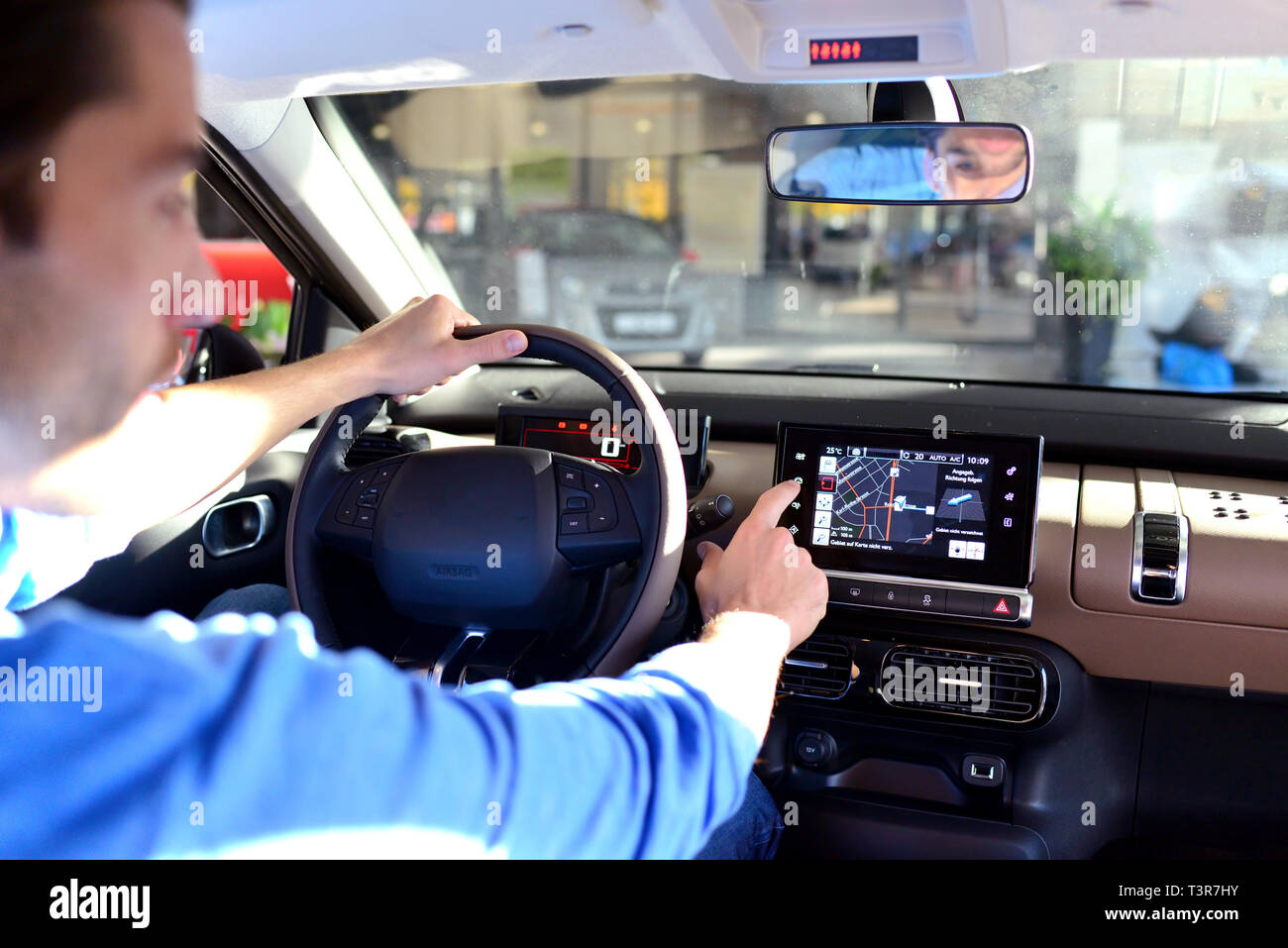 man operates navigation device in car in a car dealership and tests it ...