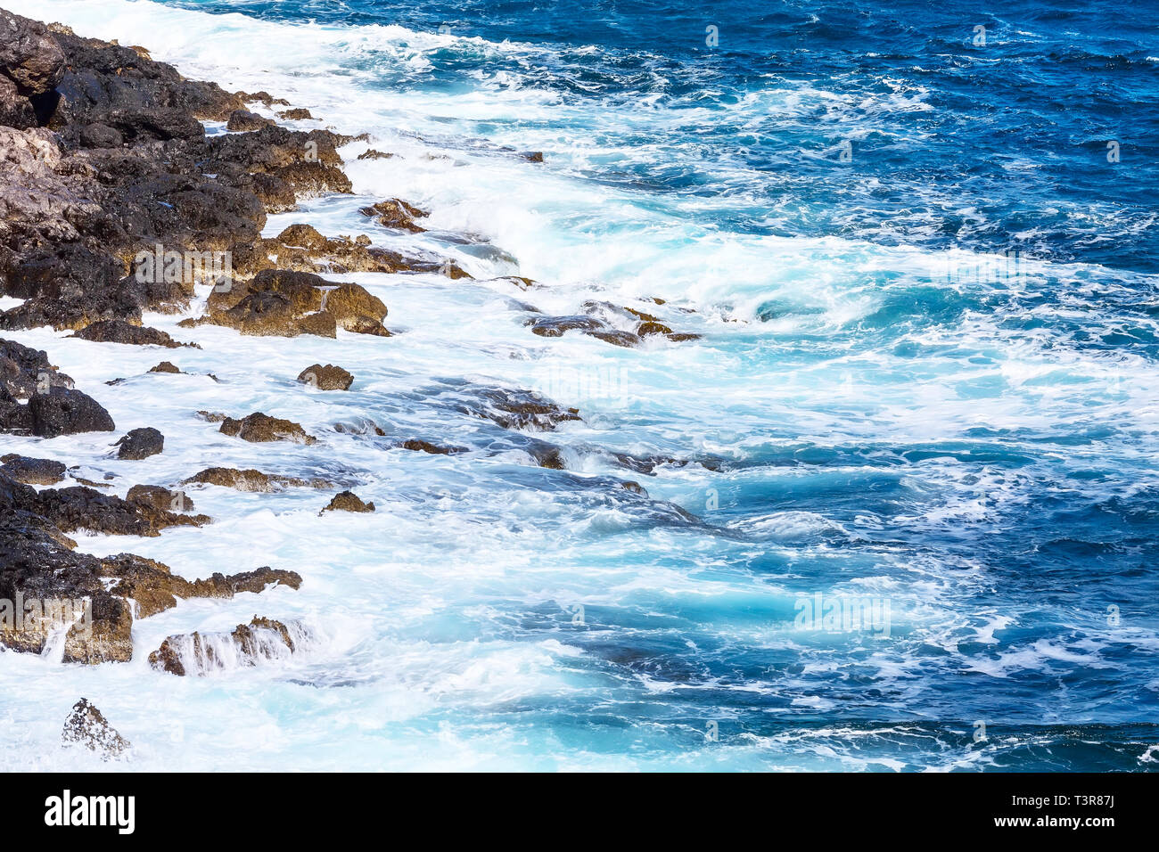 Waves hitting blue sea shore with rock stones and white foam background ...