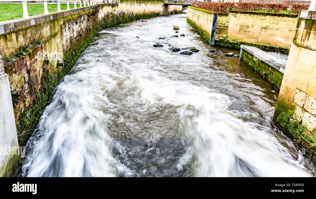 Fast running water after passing a lock in a small city river ...