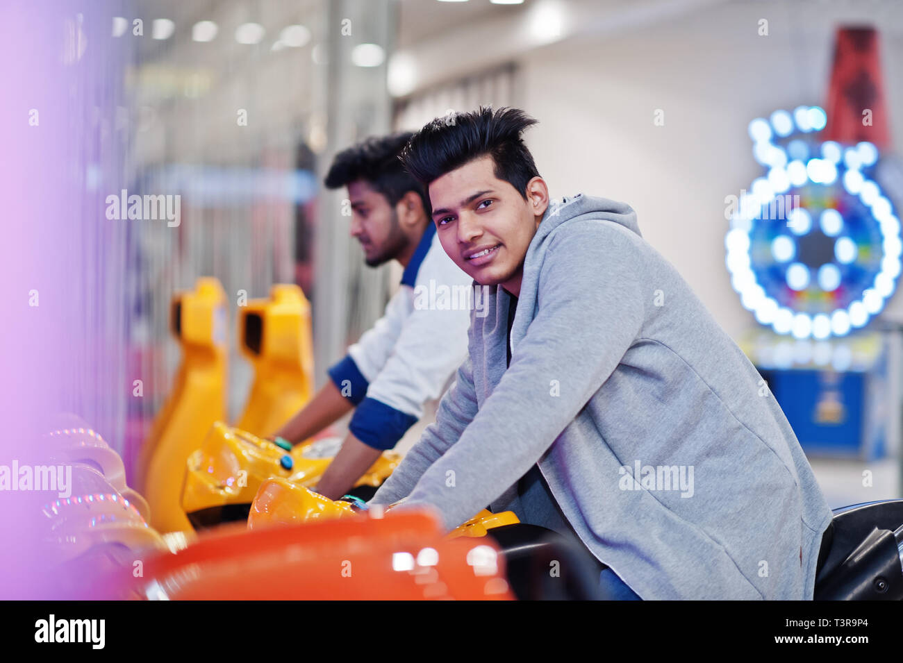 Two asian guys compete on speed rider arcade game motorcycle racing ...