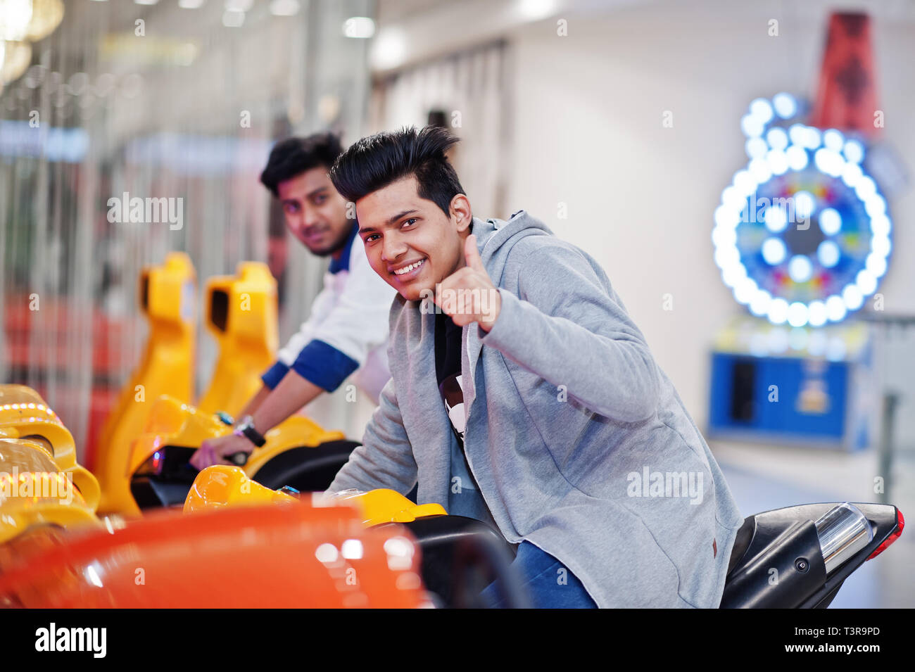 Two asian guys compete on speed rider arcade game motorcycle racing ...