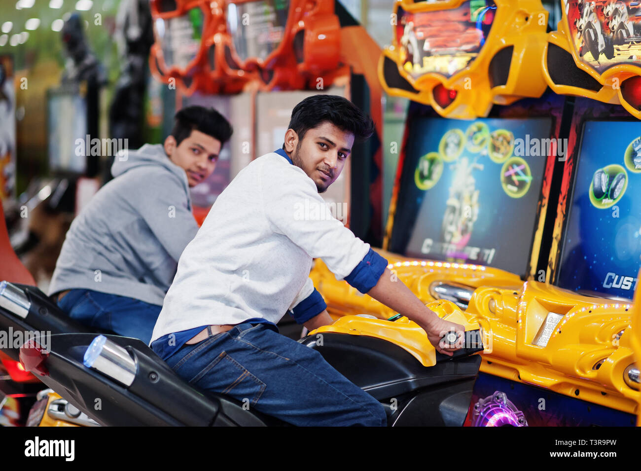 Two asian guys compete on speed rider arcade game motorcycle racing ...