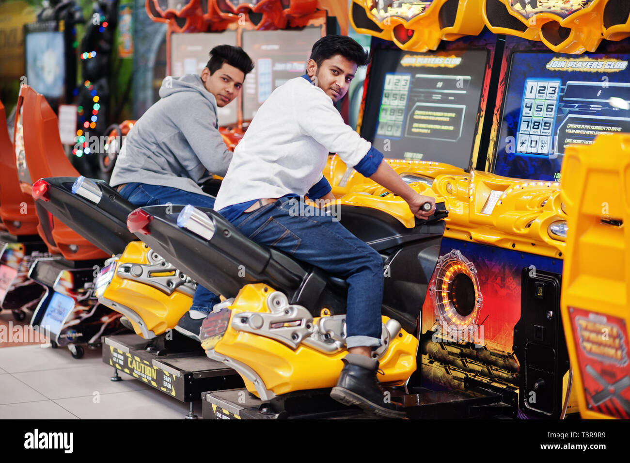 Two asian guys compete on speed rider arcade game motorcycle racing ...