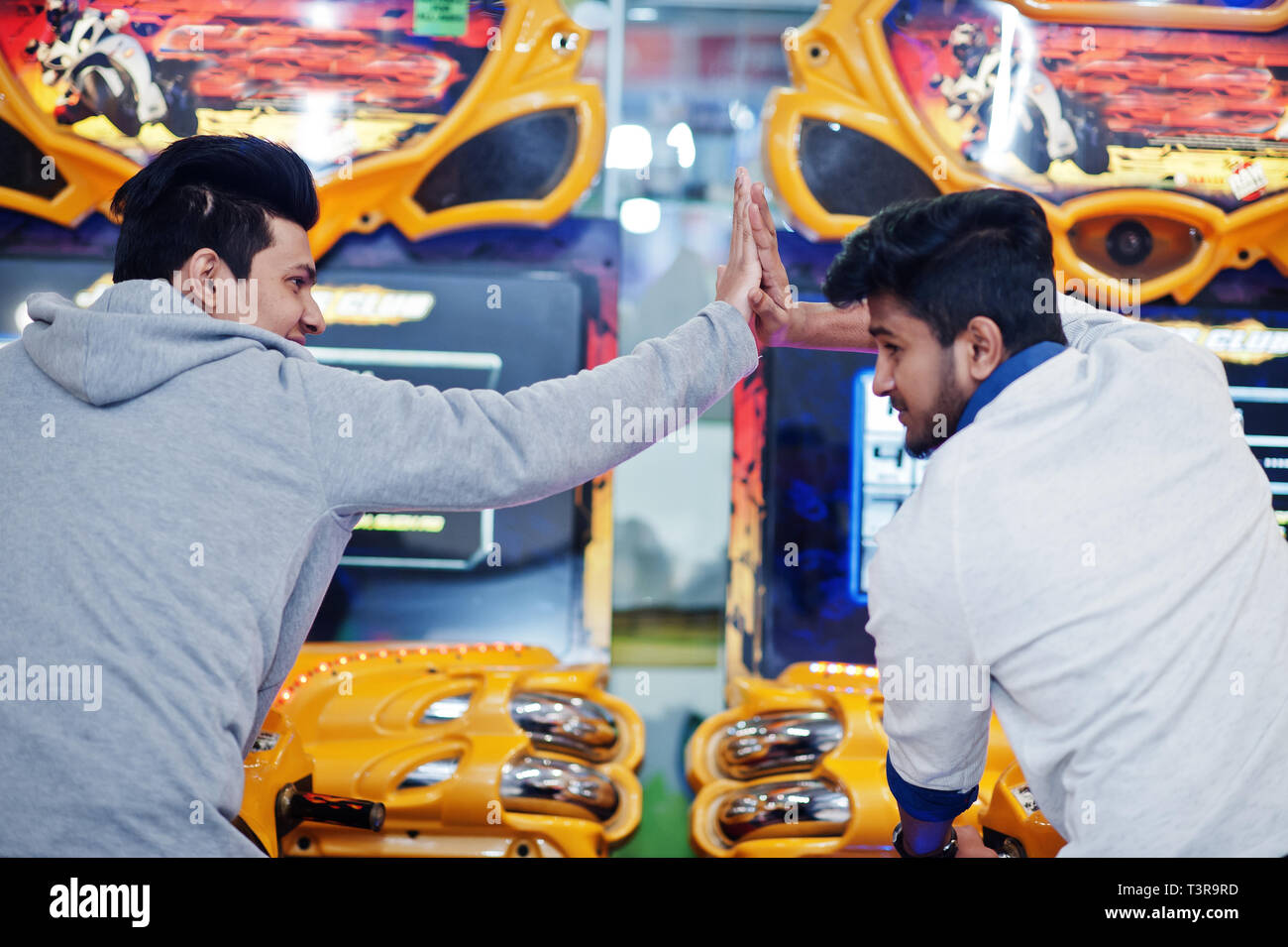Two asian guys compete on speed rider arcade game motorcycle racing ...