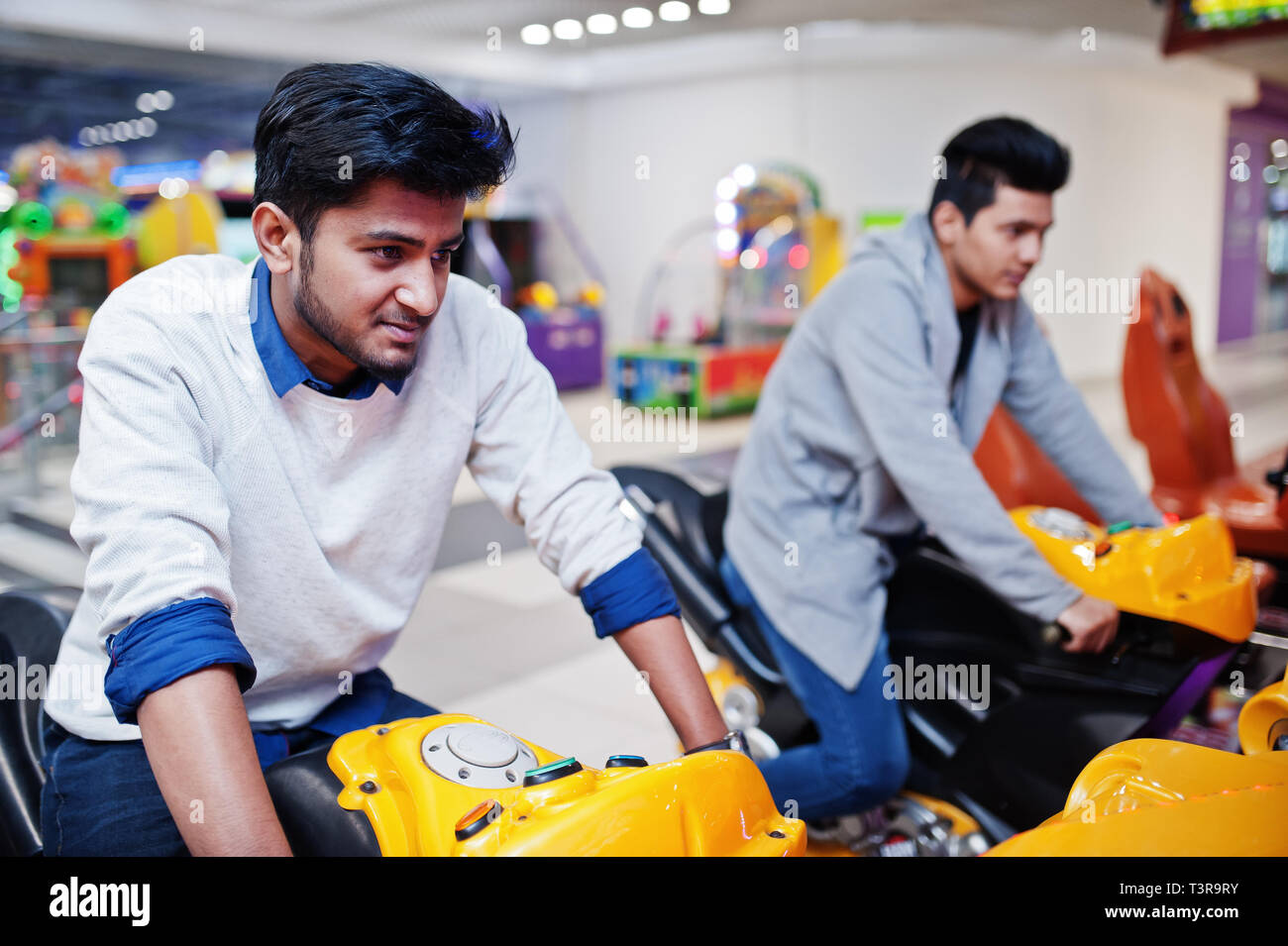 Two asian guys compete on speed rider arcade game motorcycle racing ...