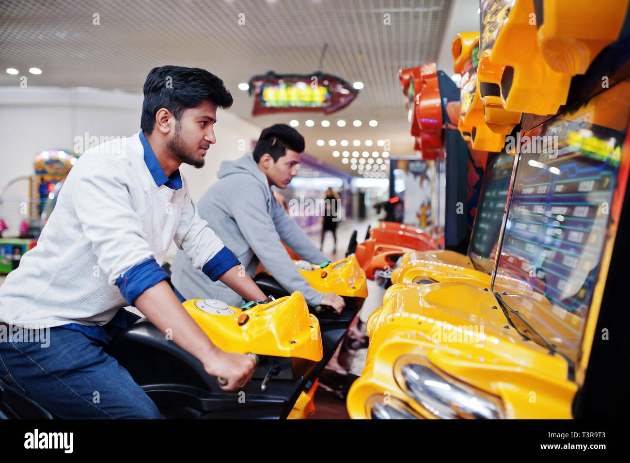 Two asian guys compete on speed rider arcade game motorcycle racing ...