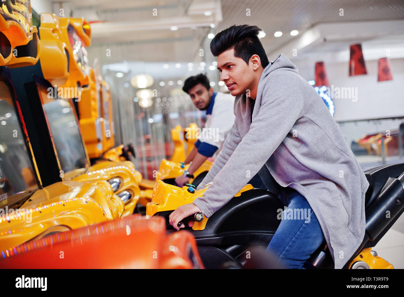 Two asian guys compete on speed rider arcade game motorcycle racing ...