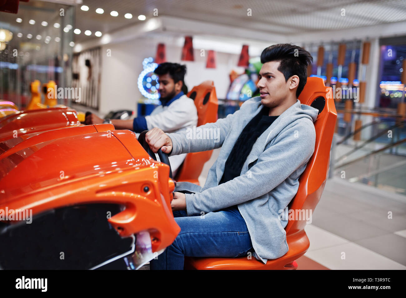 Two asian guys compete on speed rider arcade game racing simulator ...