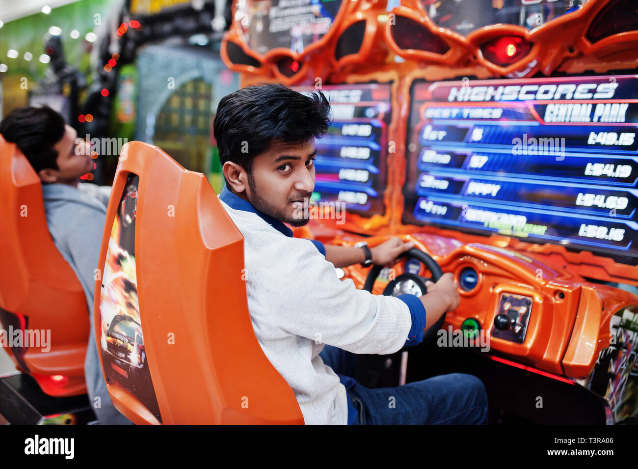 Two asian guys compete on speed rider arcade game racing simulator ...