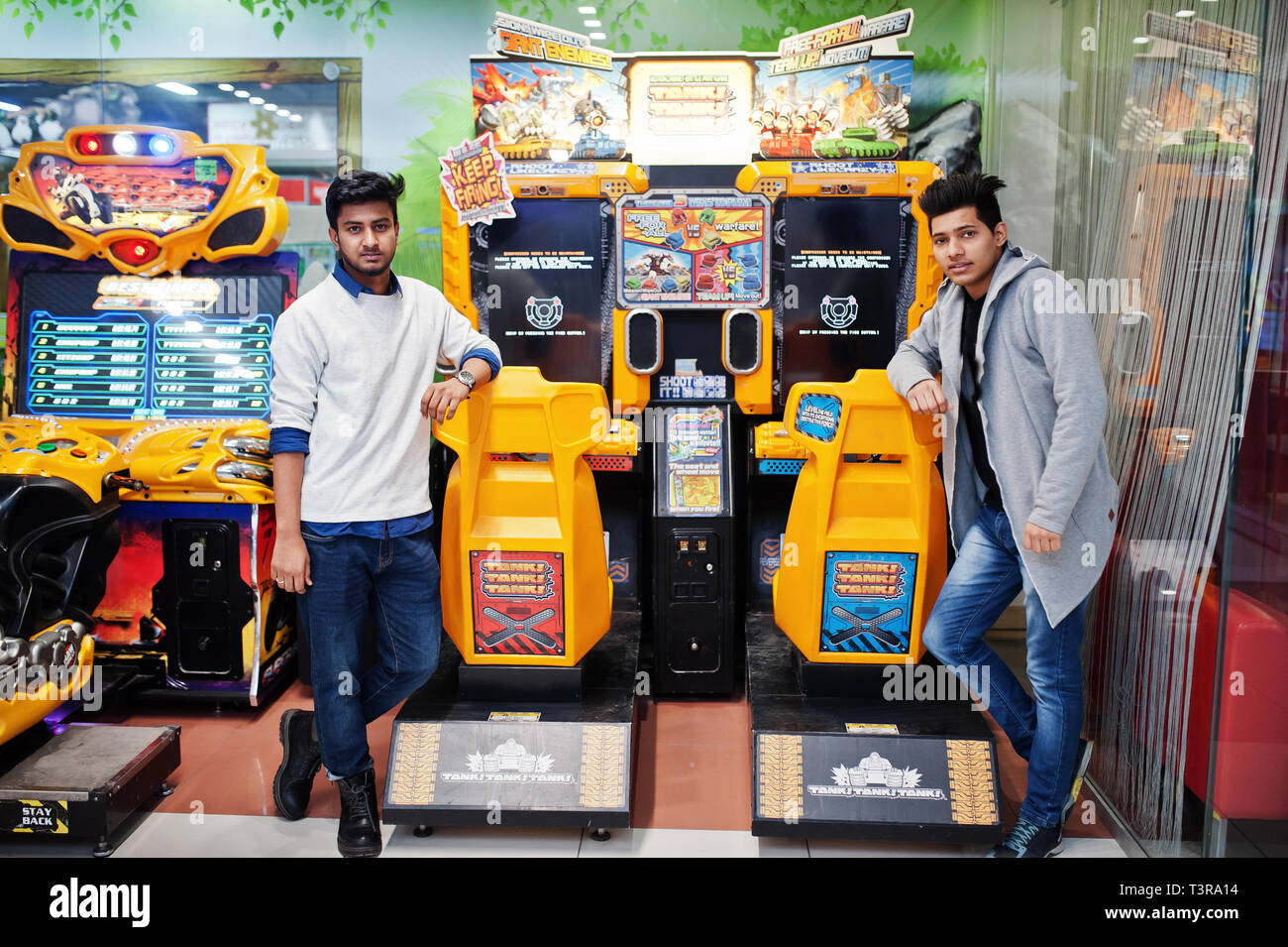 Two asian guys compete on speed rider arcade game racing simulator ...