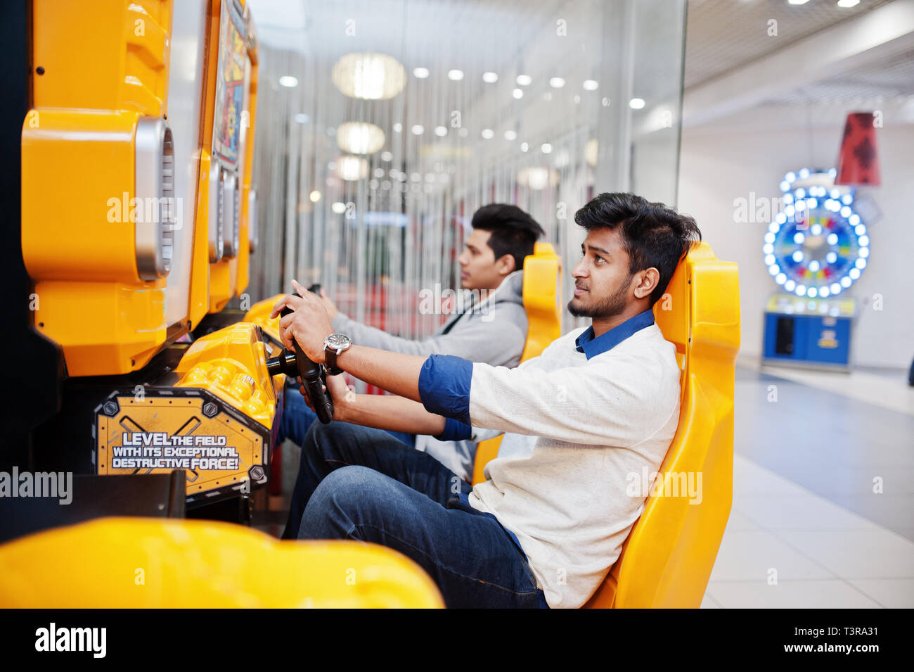 Two asian guys compete on speed rider arcade game racing simulator ...