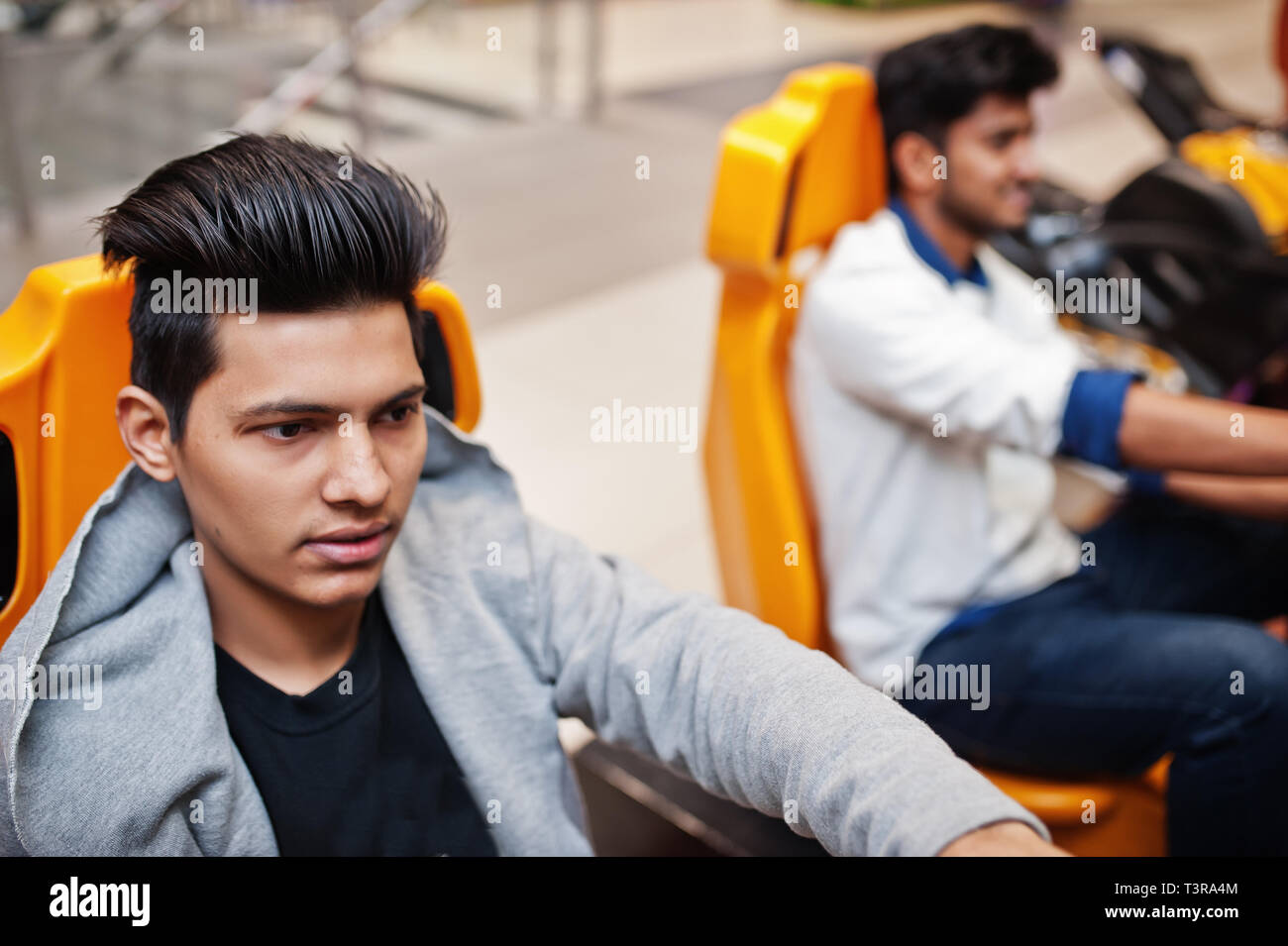 Two asian guys compete on speed rider arcade game racing simulator ...