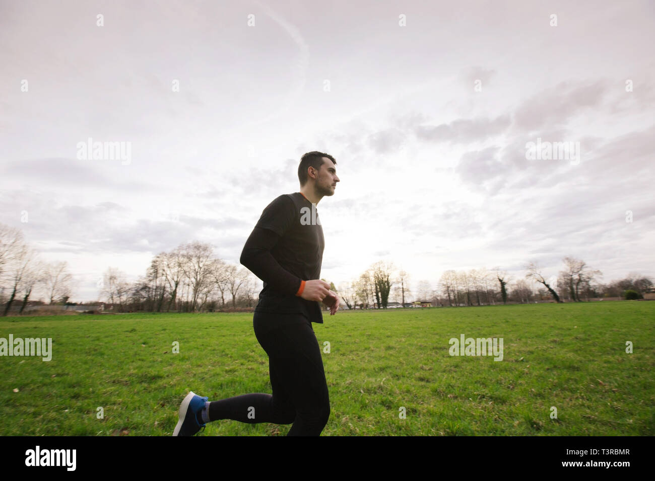 Male athlete running, exercising indoors, jogging side view, full ...