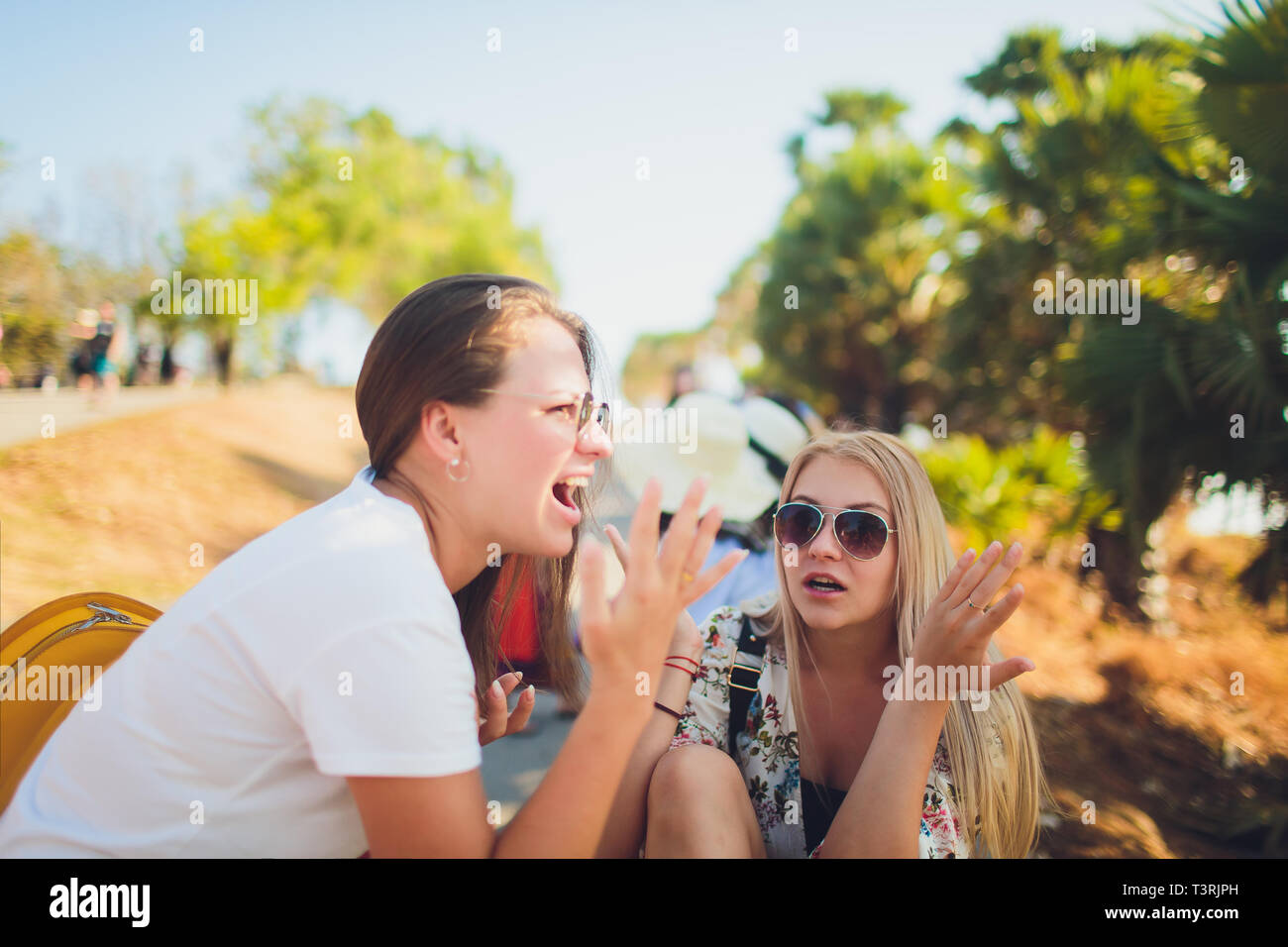 Friendly talk. Two beautiful young women walking along the street and ...