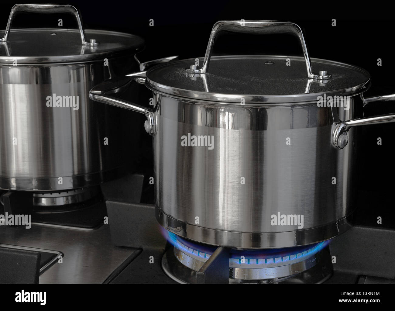Metal pots in the kitchen, gas stove on, blue flame burning Stock Photo ...