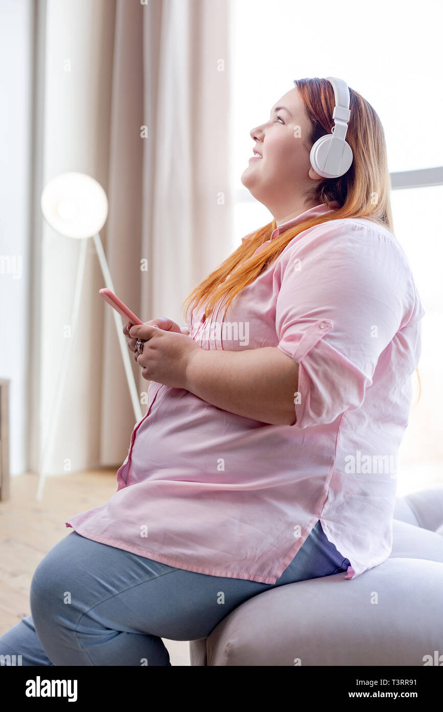 Joyful overweight young woman listening to music Stock Photo - Alamy