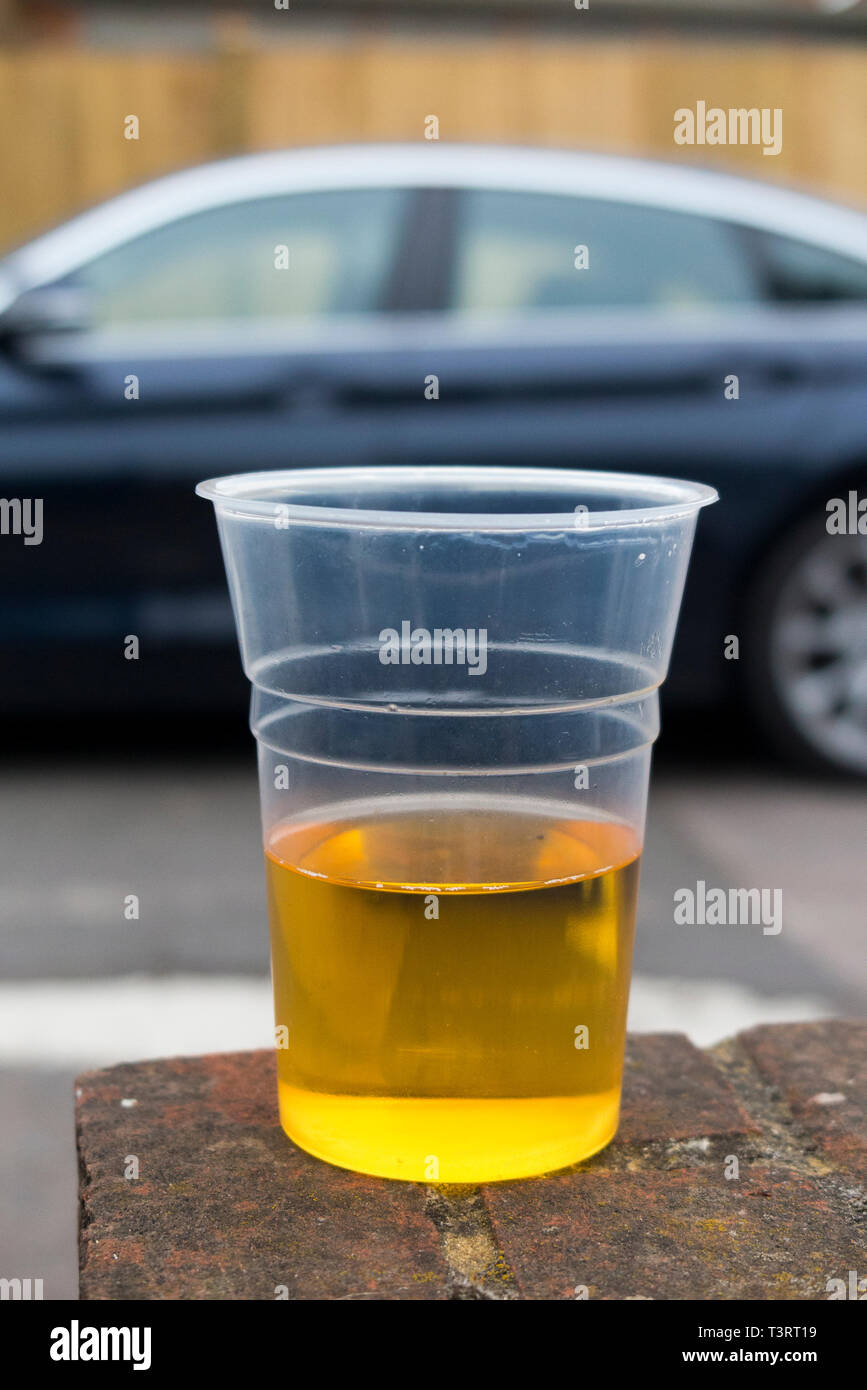 Parked car and a half empty plastic beaker of lager to illustrate the ...