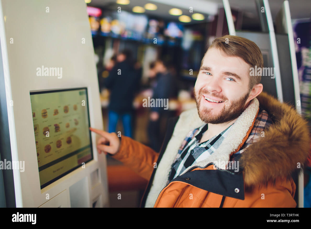A man orders food in the touch screen terminal with electronic menu in ...
