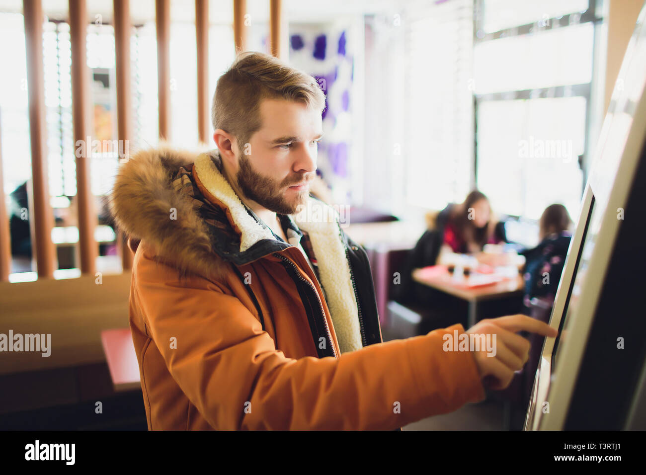 A man orders food in the touch screen terminal with electronic menu in ...