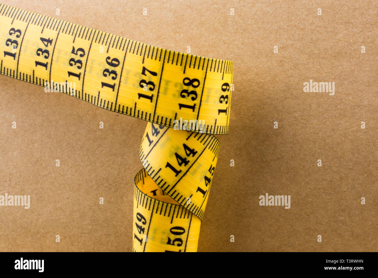 Yellow color Tape measure roll on a brown background Stock Photo - Alamy