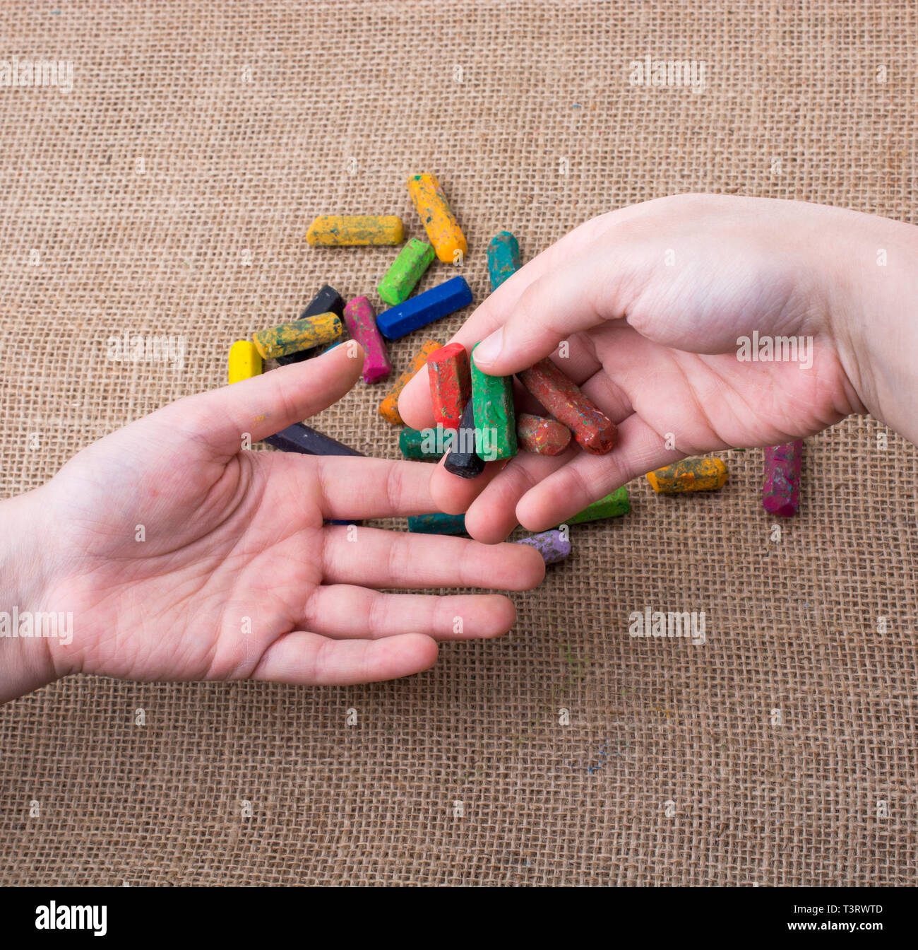 Used color crayons and a hand giving out some Stock Photo - Alamy