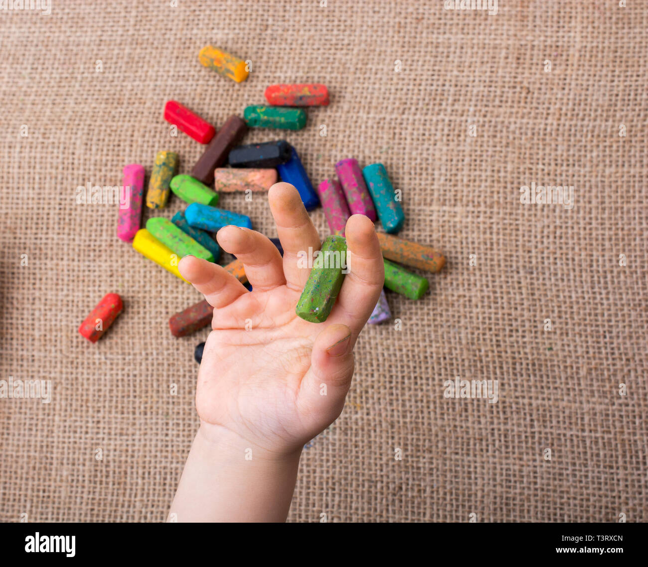 Used color crayons and a toddlers hand holding one Stock Photo - Alamy