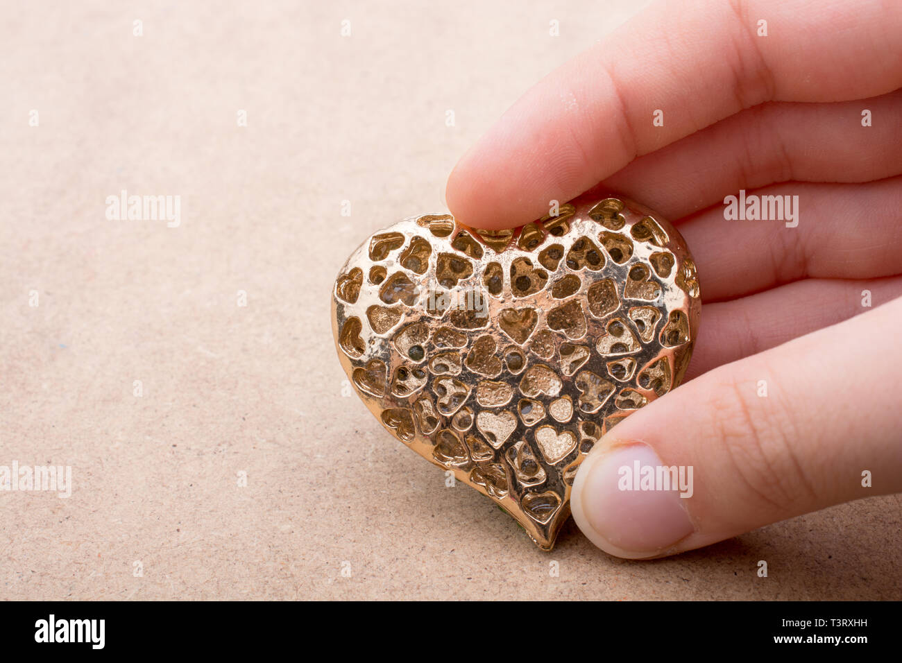 Heart shaped gold color metal object in hand Stock Photo - Alamy