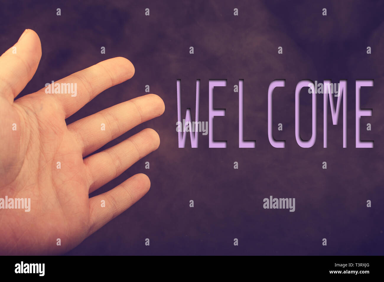 Hand making a welcome gesture on a dark background Stock Photo - Alamy