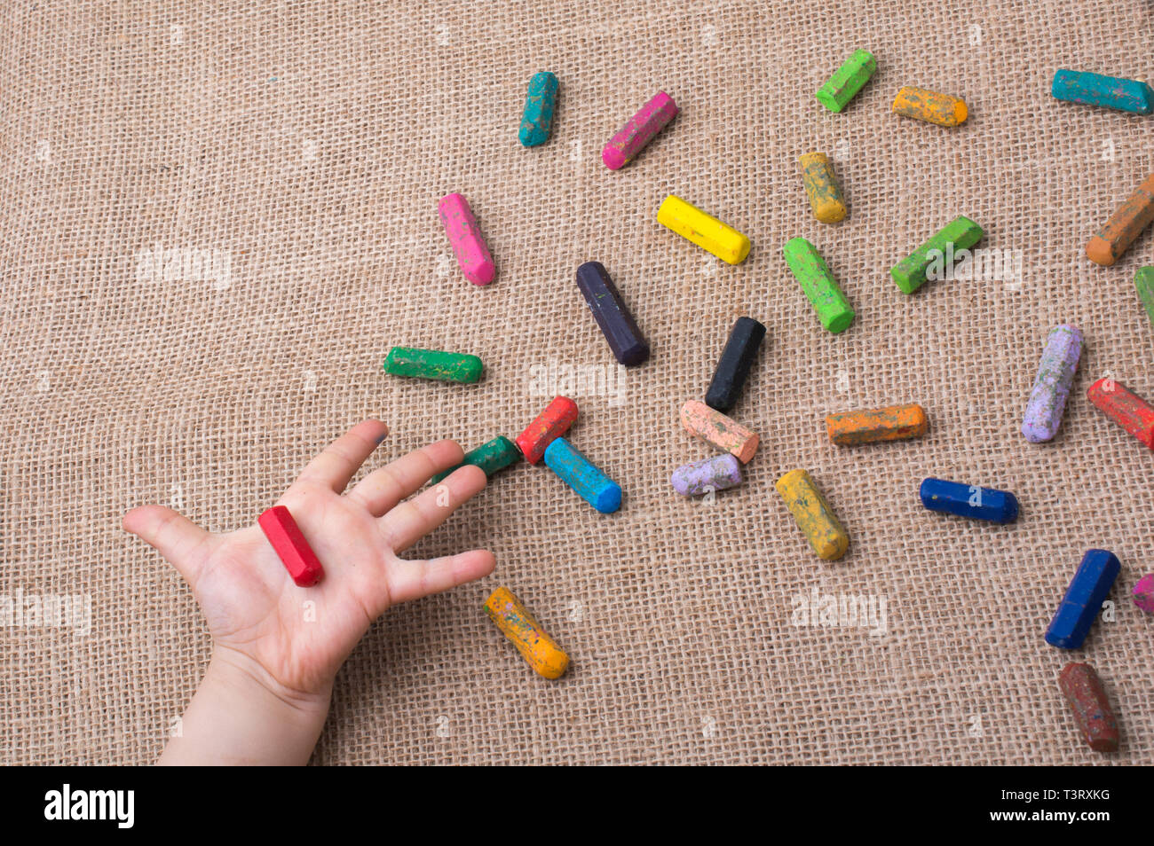 Used color crayons and a toddlers hand holding one Stock Photo - Alamy