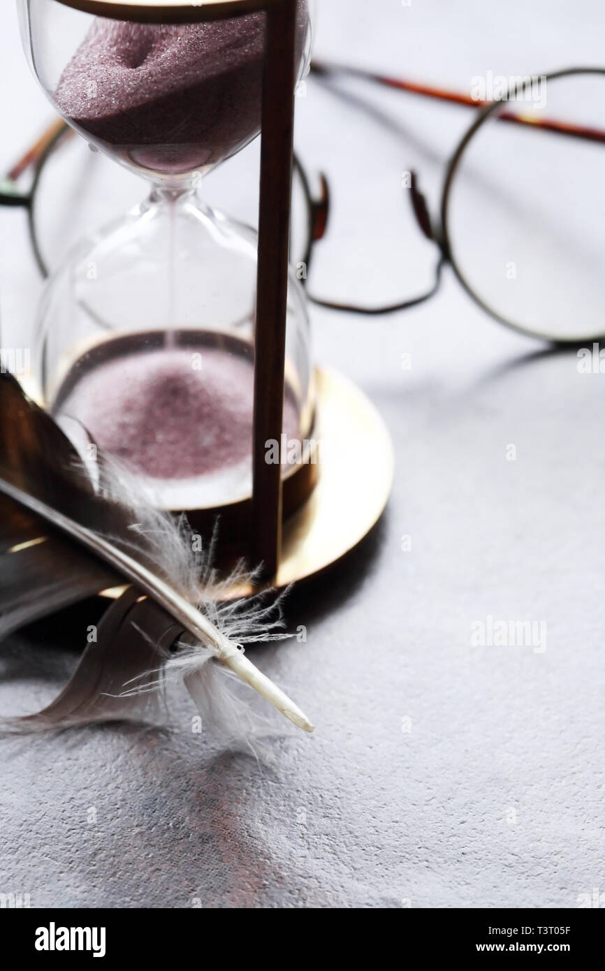 Vintage still life with hourglass near feather and old spectacles Stock ...