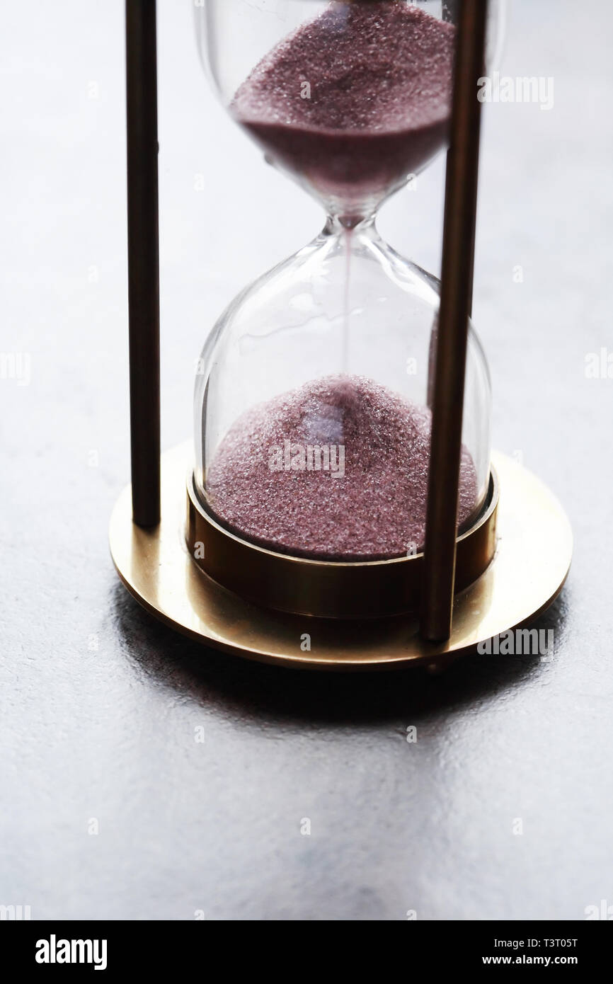 Vintage hourglass with flowing sand on dark background Stock Photo - Alamy