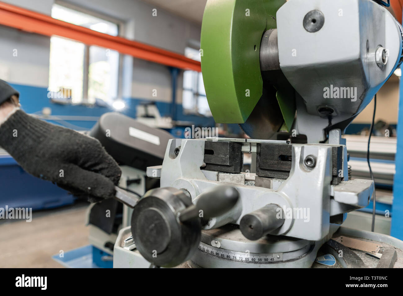 worker cuts a piece of material with a circular saw machine. Industrial ...