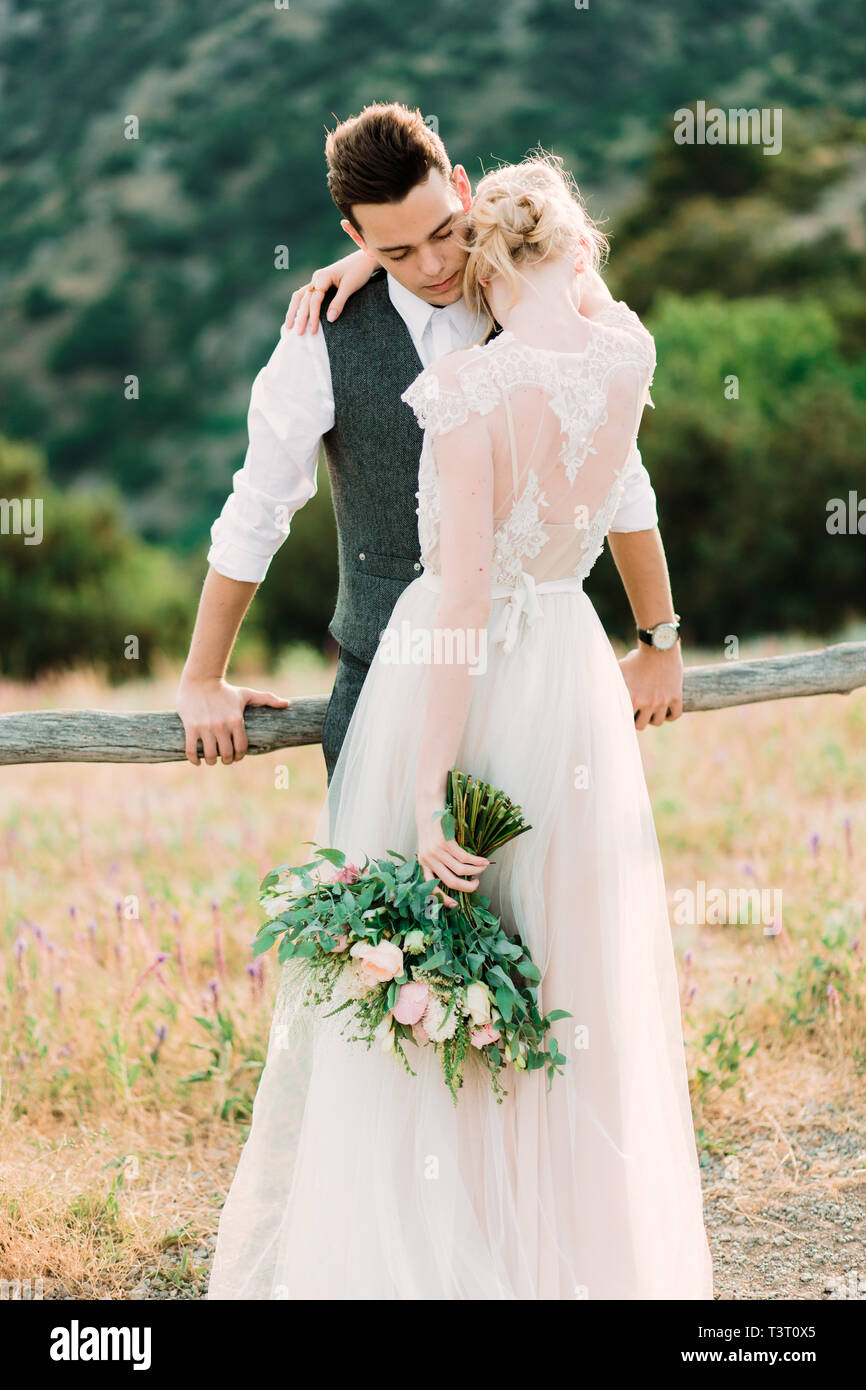 Beautiful bride and groom hug each other tender standing on the golden ...