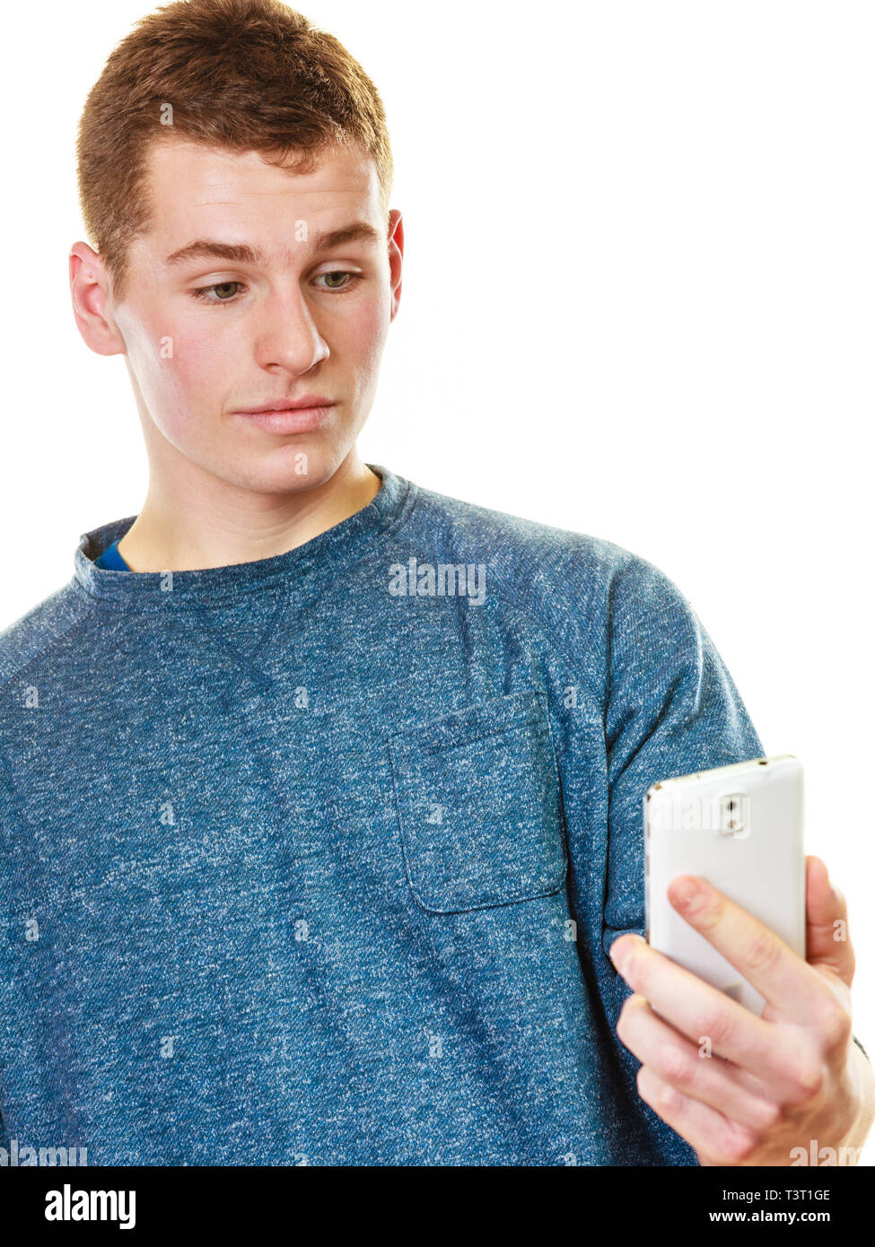 Teen boy texting on the mobile phone. Young man reading sms on ...
