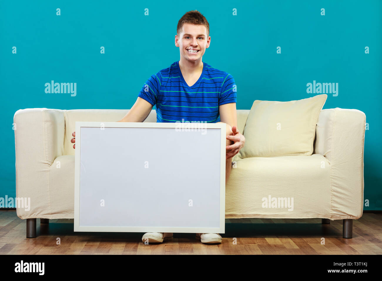 Advertisement concept. Young man sitting on sofa with blank ...