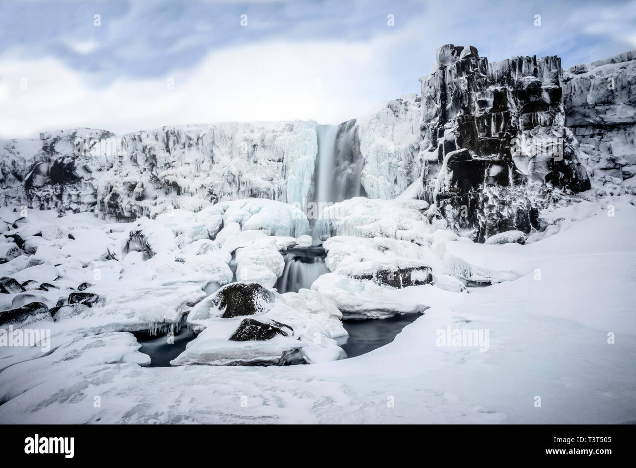 Waterfall pouring over icy cliffs in remote landscape Stock Photo - Alamy