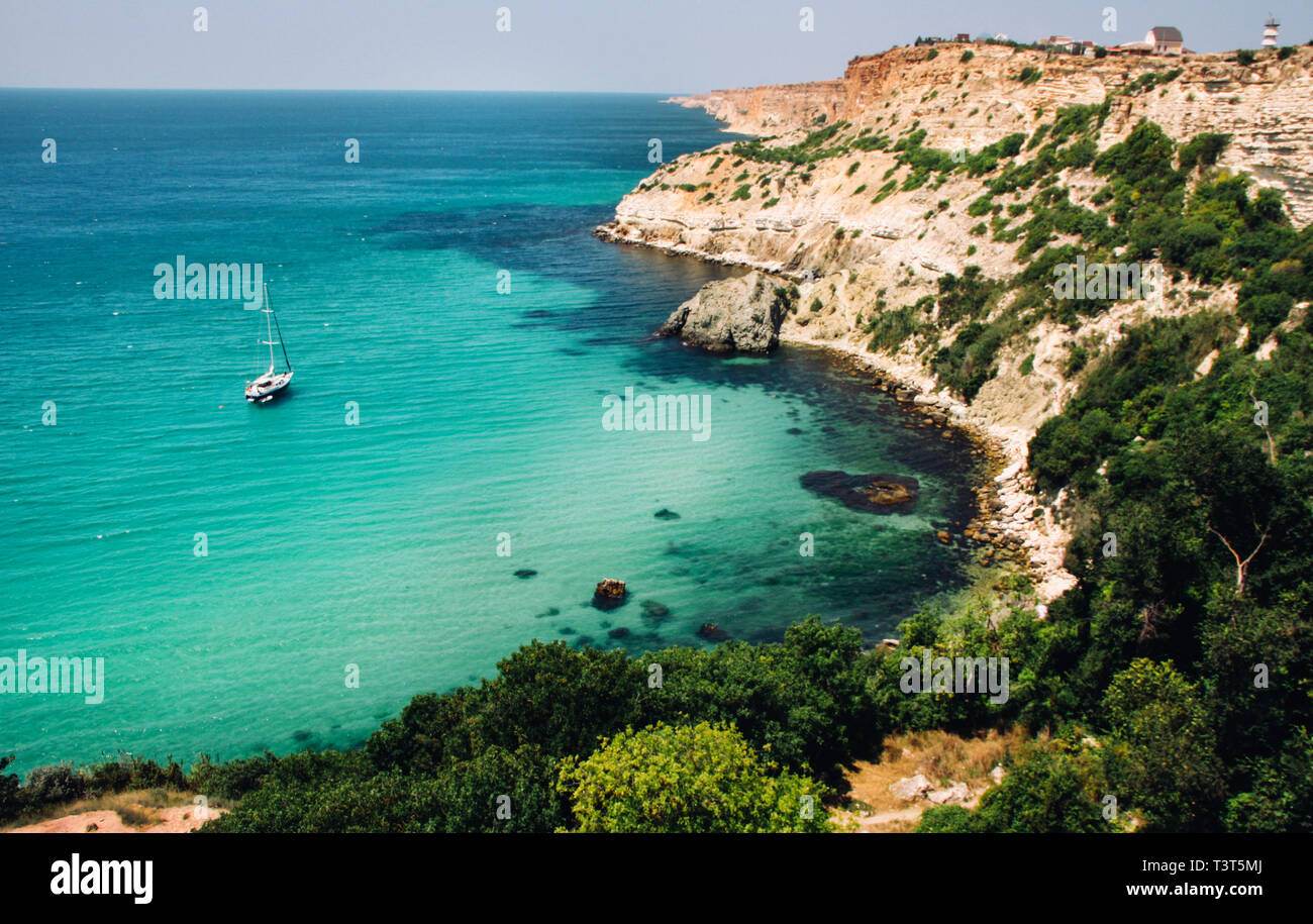 Beautiful seascape bay with a yacht, rocks and greenery. Vivid ...