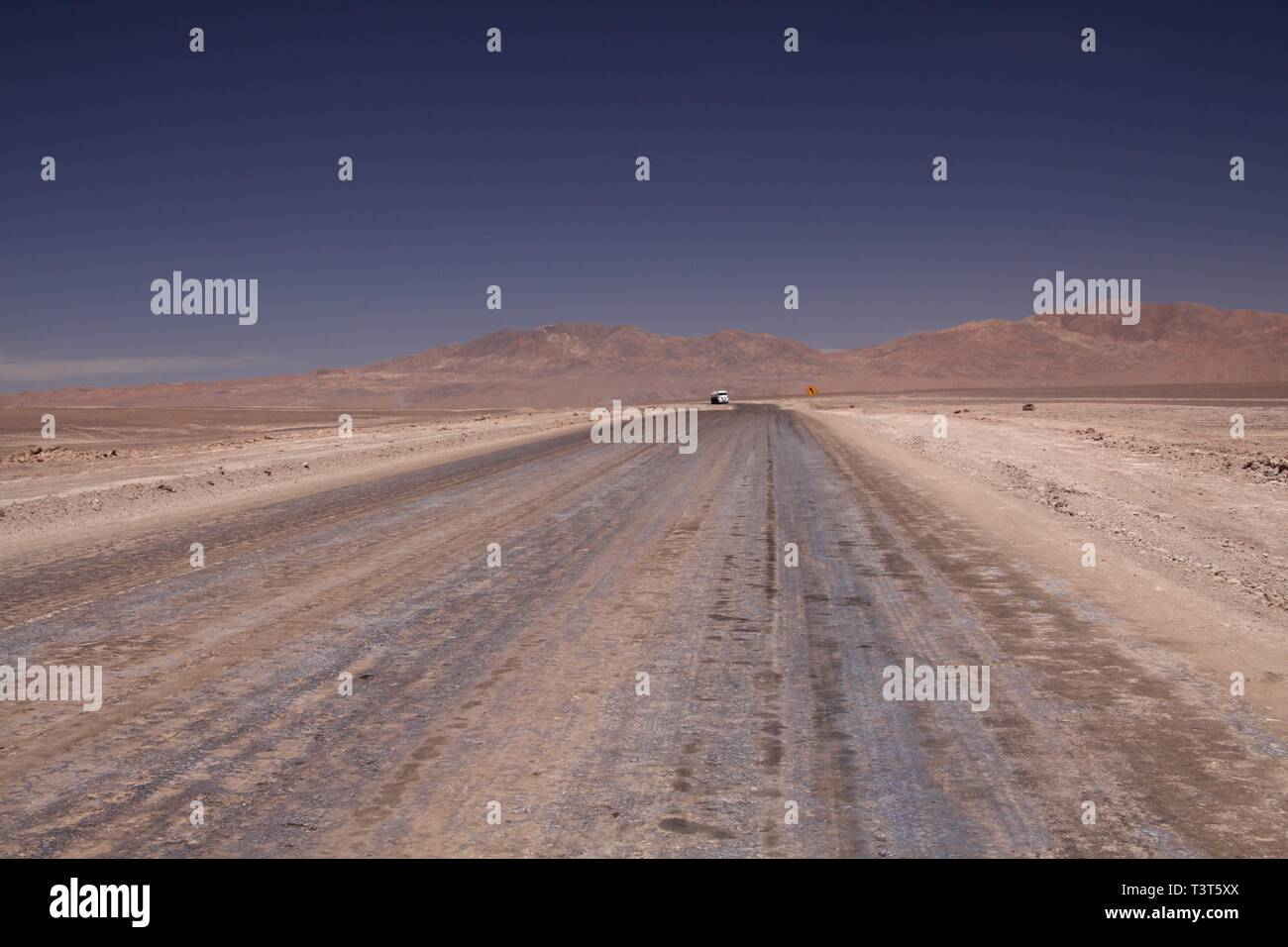 Endless dirt road to infinity of salt flat plateau contrasting with ...