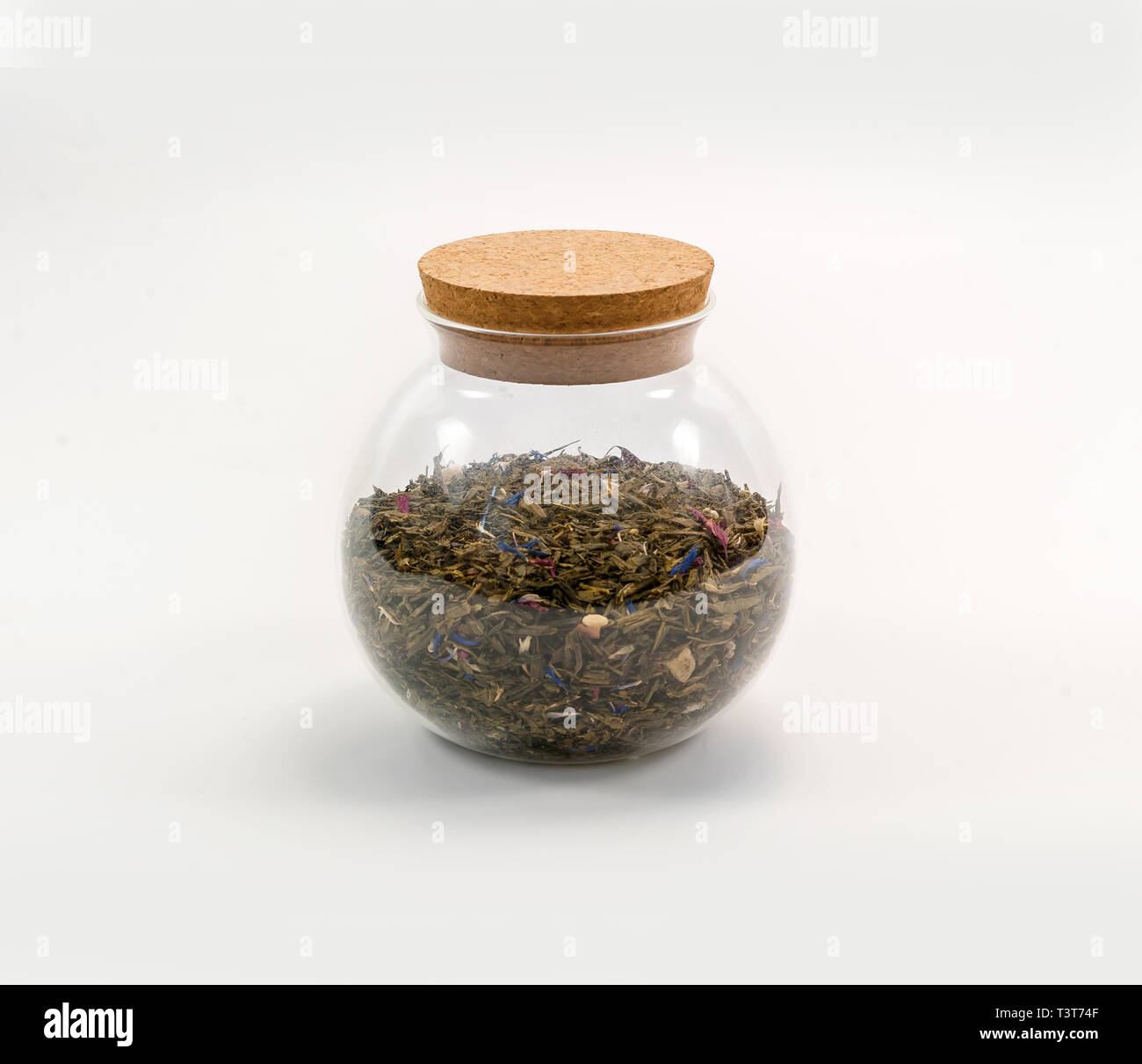 Round glass jar with a cork filled with aromatic tea with dried flowers ...