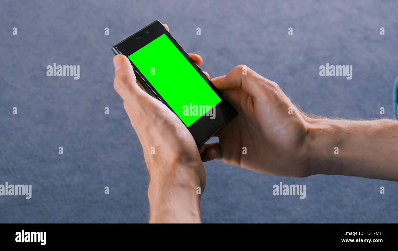 Man looking at smart phone with green screen Stock Photo - Alamy