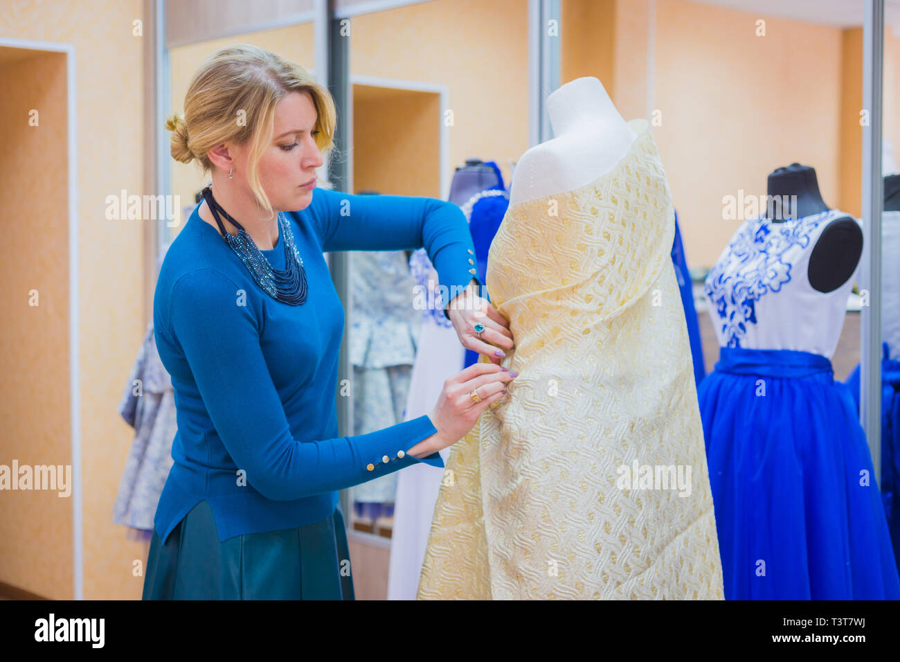 Fashion designer working with new model tailoring dress on mannequin ...