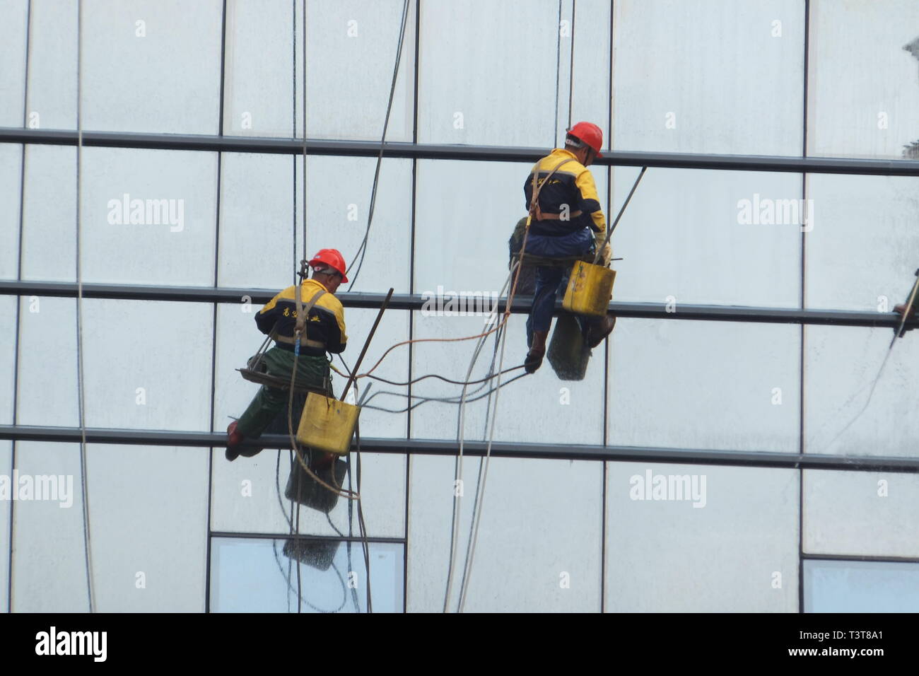 Workers clean the glass facade of a skyscraper in shenzhen, China Stock ...