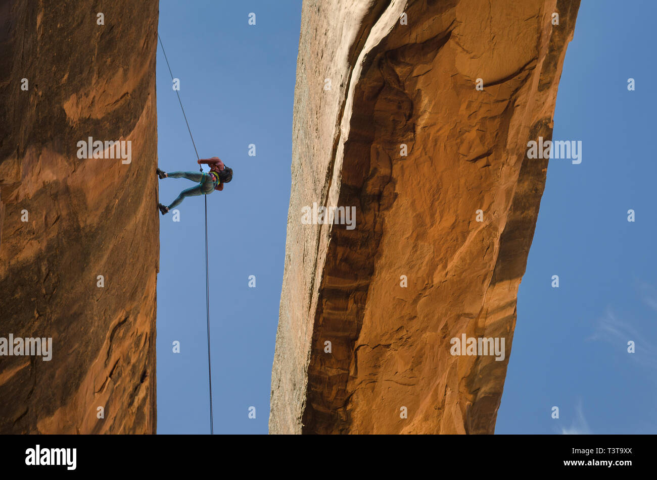 Rock climber using rope on arch Stock Photo - Alamy