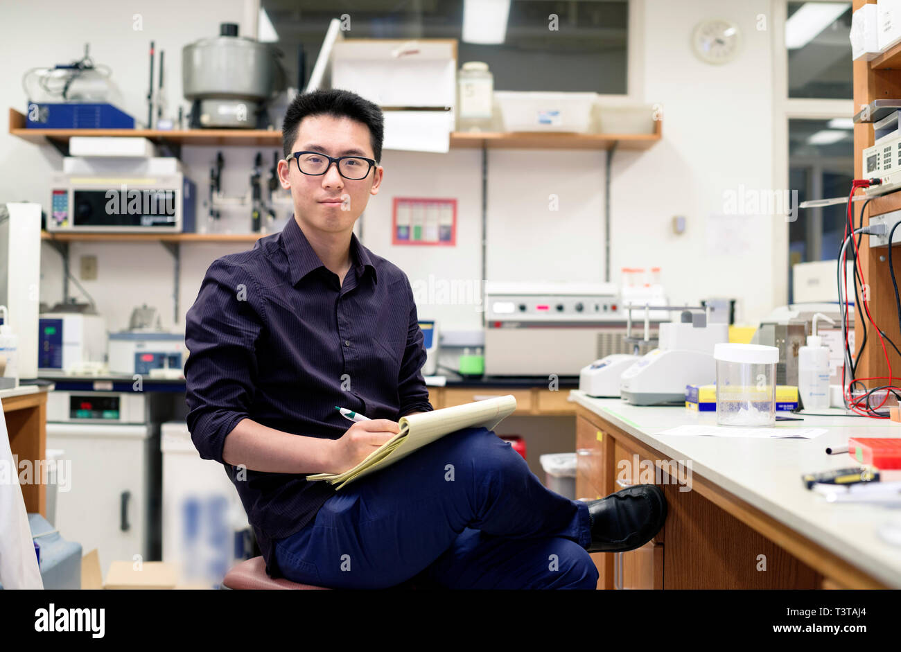 Asian man writing on notepad in electronics workshop Stock Photo - Alamy
