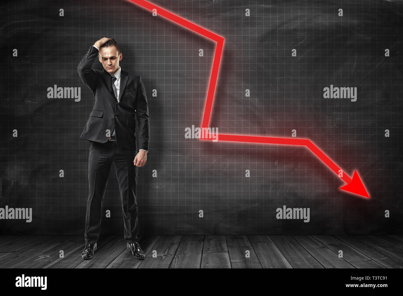 Businessman in black suit standing with one hand on head and with ...